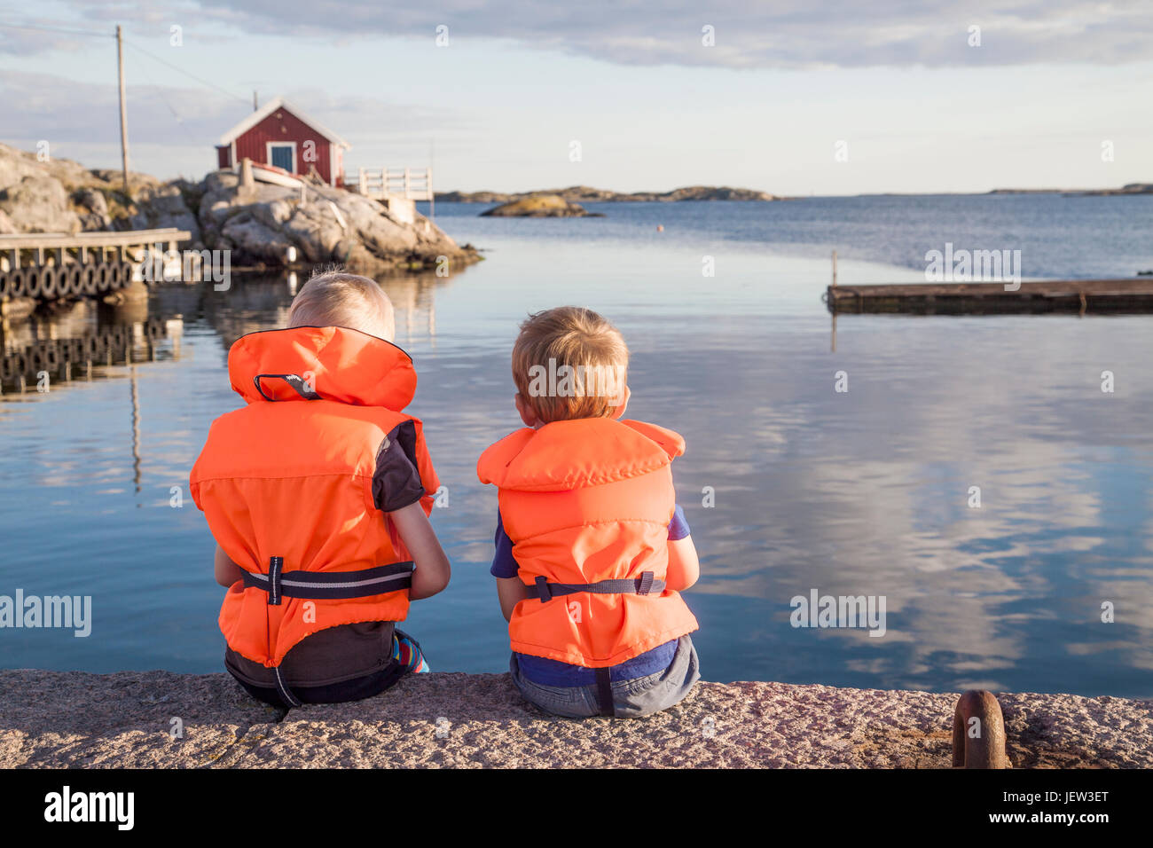 Boys sitting on jetty Stock Photo - Alamy