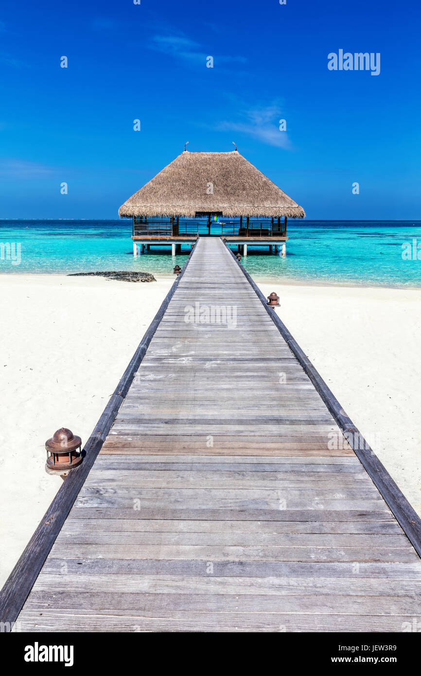 Wooden jetty leading to relaxation lodge. Maldives islands resort on ...