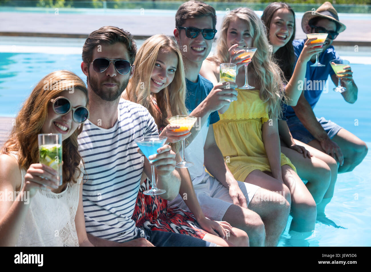 Happy friends sitting in swimming pool Stock Photo - Alamy
