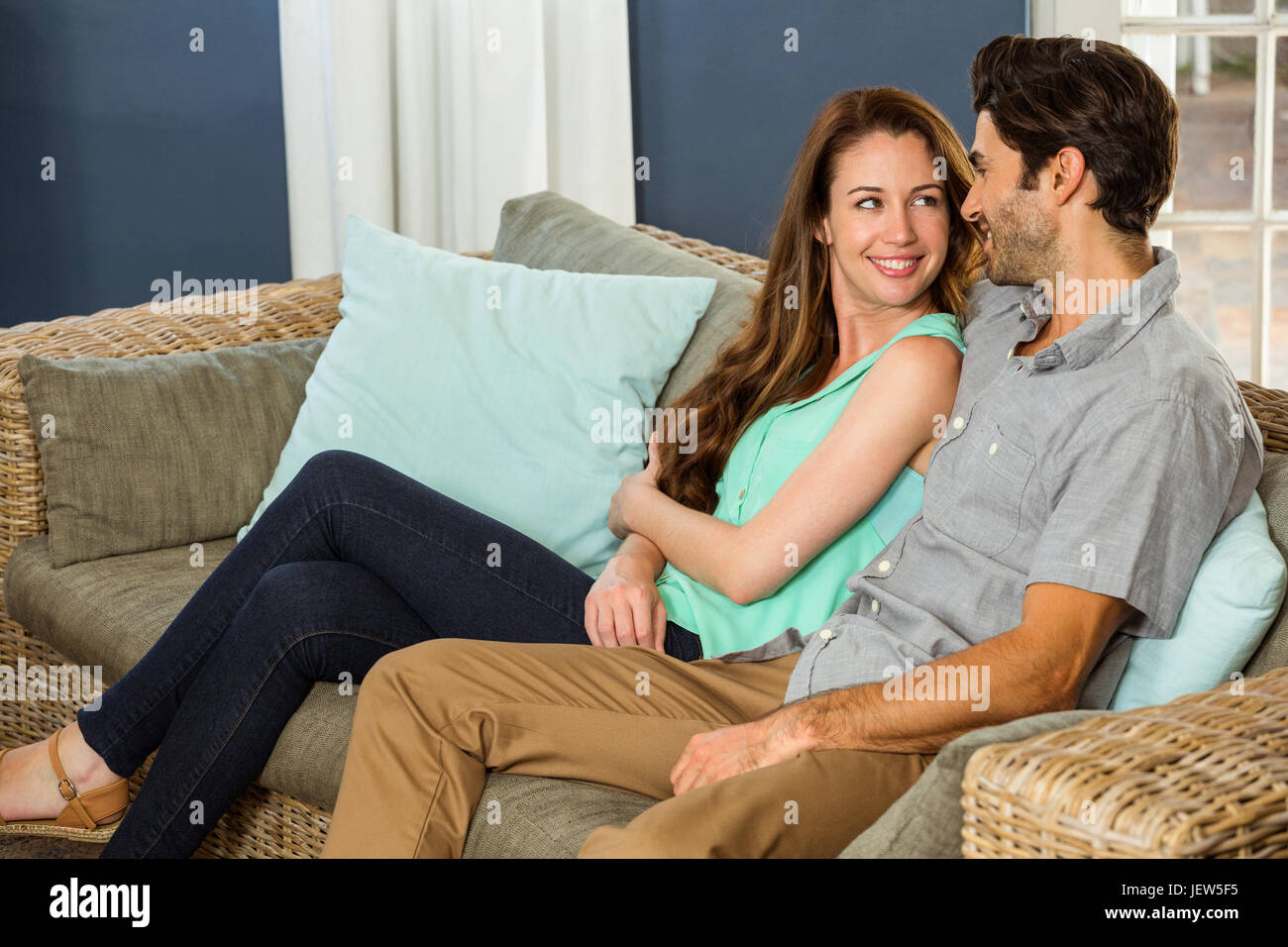 Young couple sitting together in sofa Stock Photo - Alamy