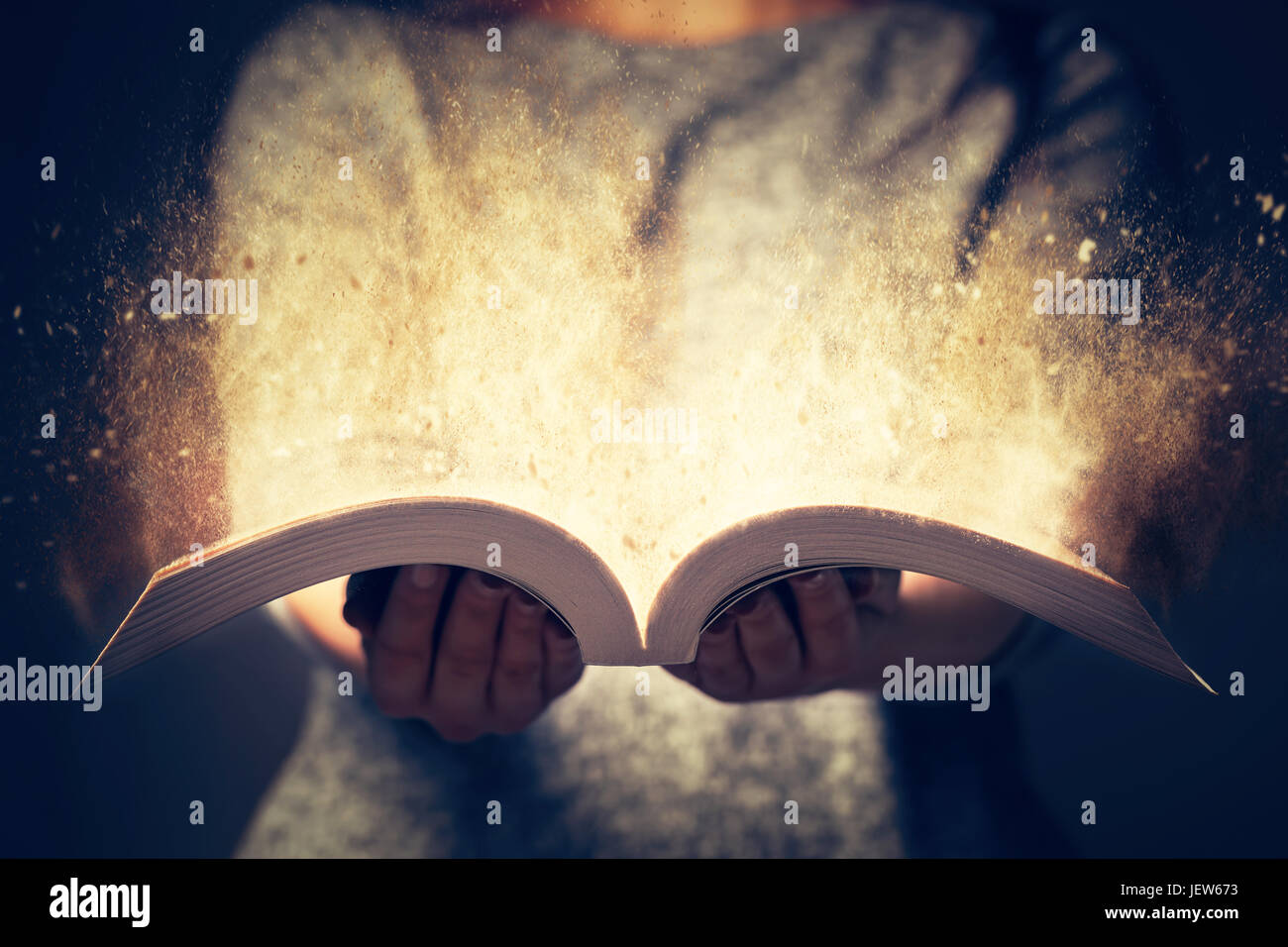 Woman holding an open book with two hands. Light coming out of the book ...
