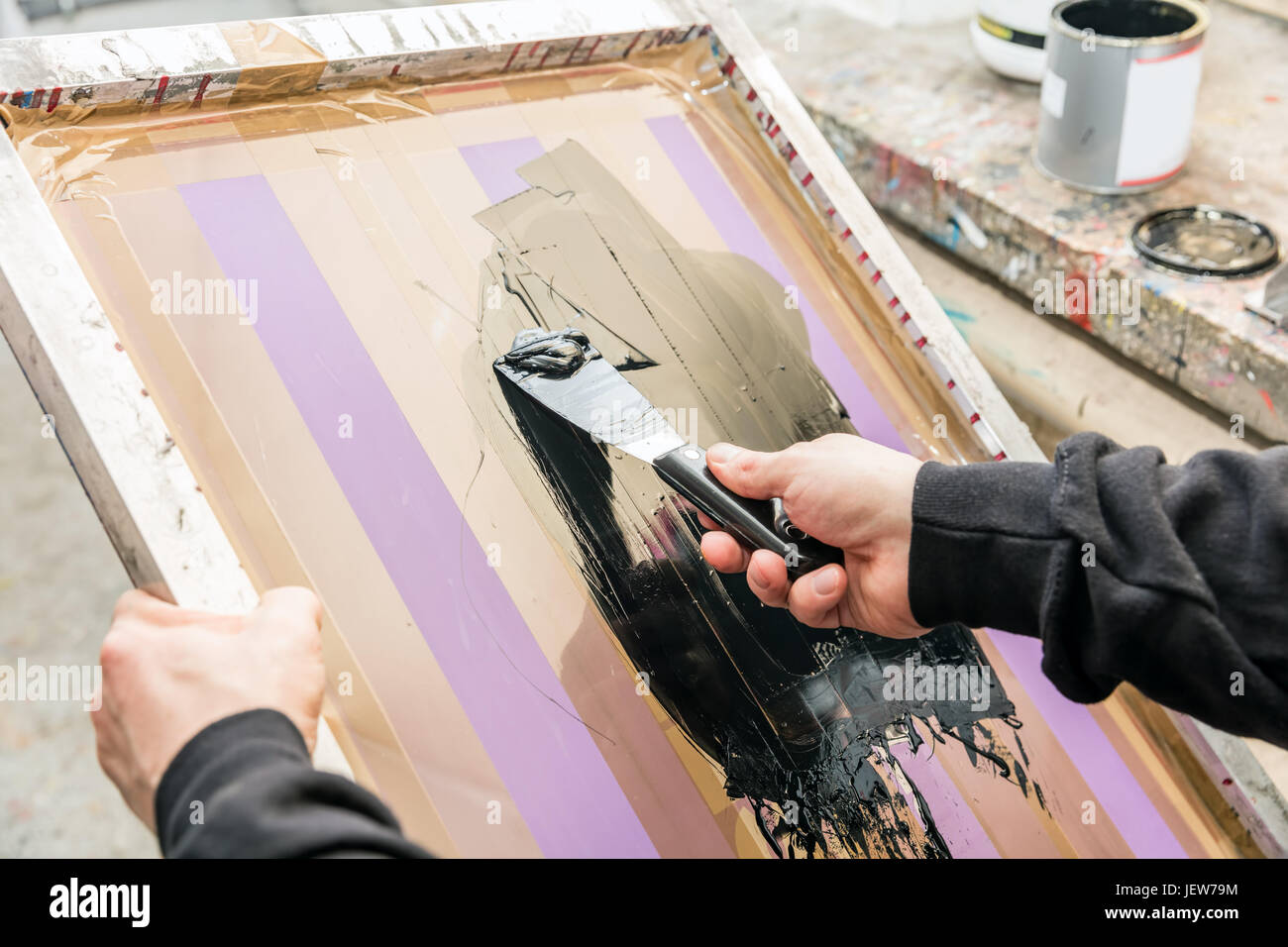 Man squeegeeing silkscreen in a workshop. Serigraphy industry ...