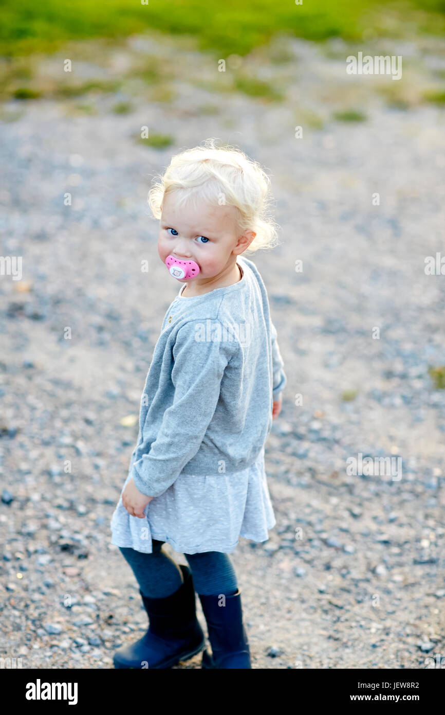 Girl with pacifier looking at camera Stock Photo - Alamy