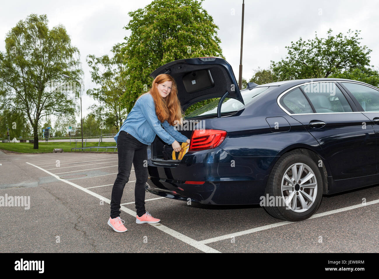 Woman putting backpack in car boot Stock Photo - Alamy