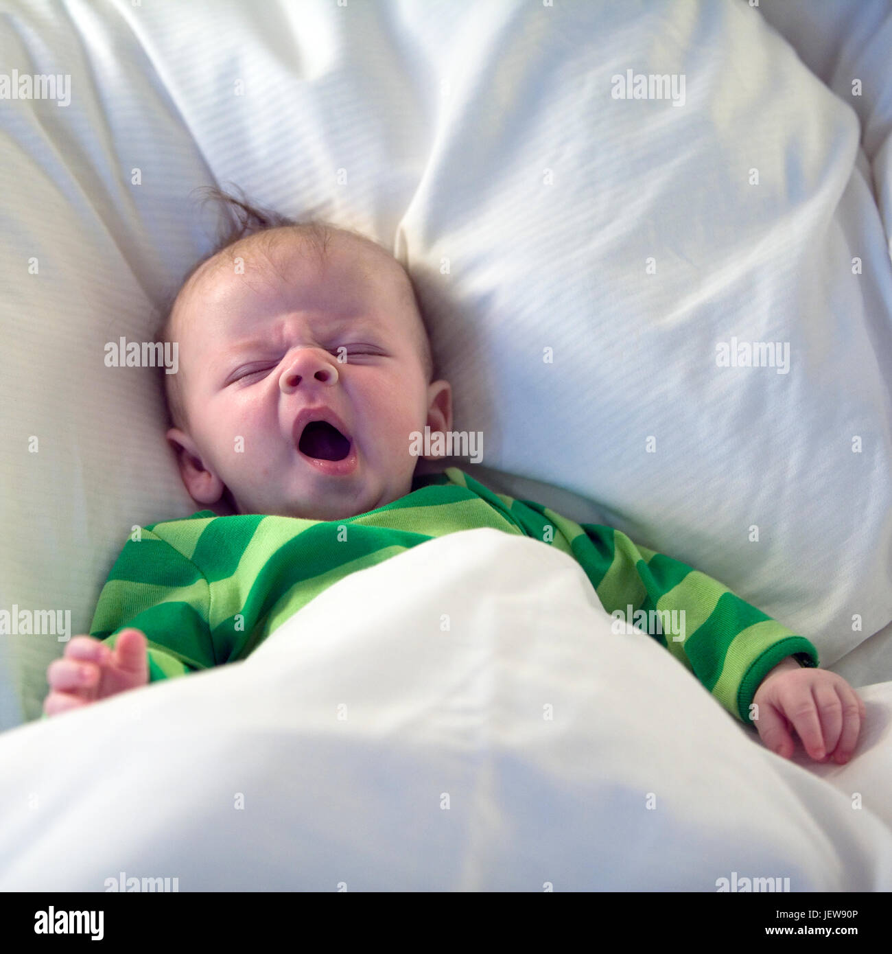 Yawning baby in bed Stock Photo - Alamy