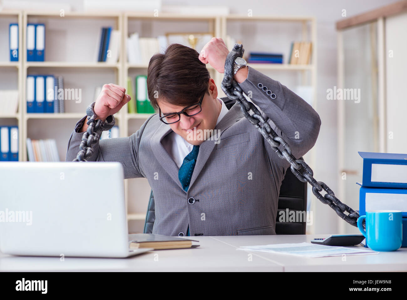 Businessman tied with chains to his work Stock Photo - Alamy