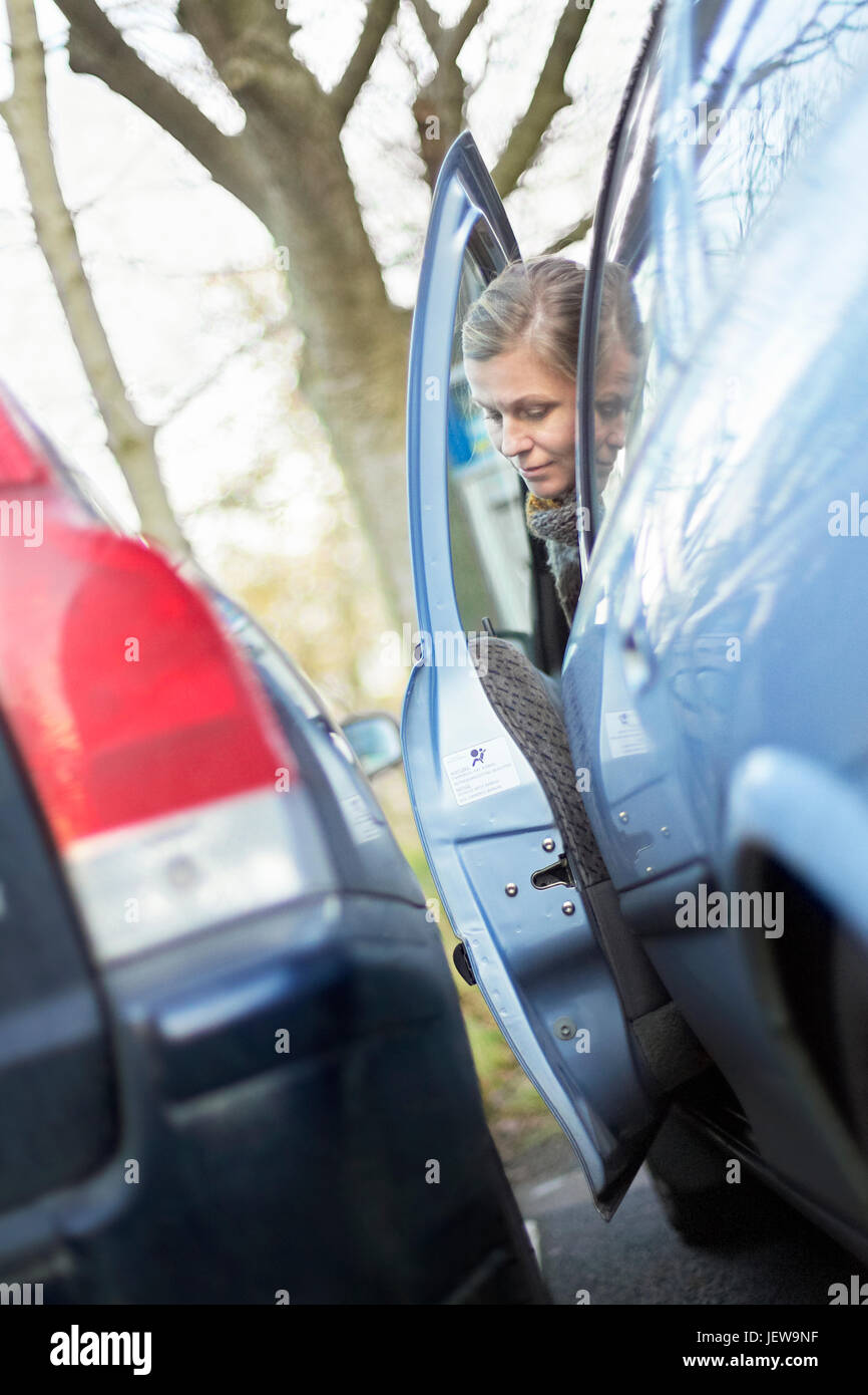 Woman trying to leave car in tiny parking space Stock Photo - Alamy