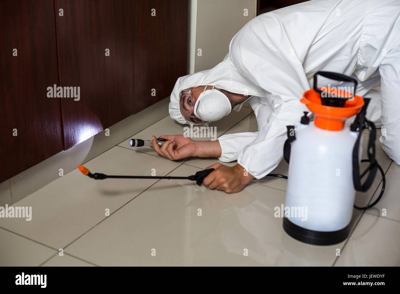 Worker using flashlight under cabinet Stock Photo - Alamy