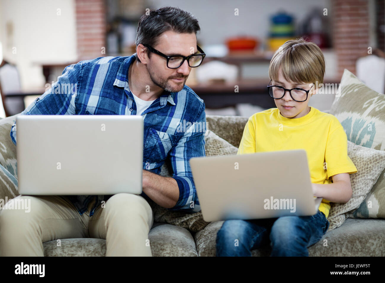 Father and son using laptop in living room Stock Photo - Alamy