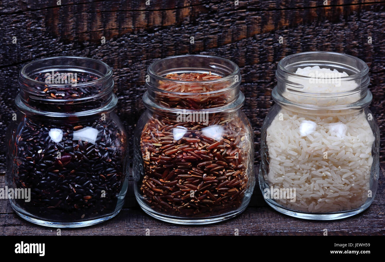 Jars with different types of rice on wooden table Stock Photo - Alamy