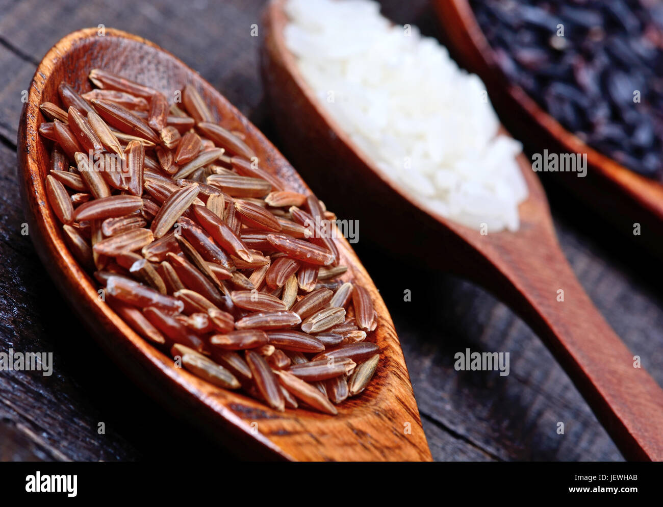 Wooden spoons with various types of rice on table Stock Photo - Alamy