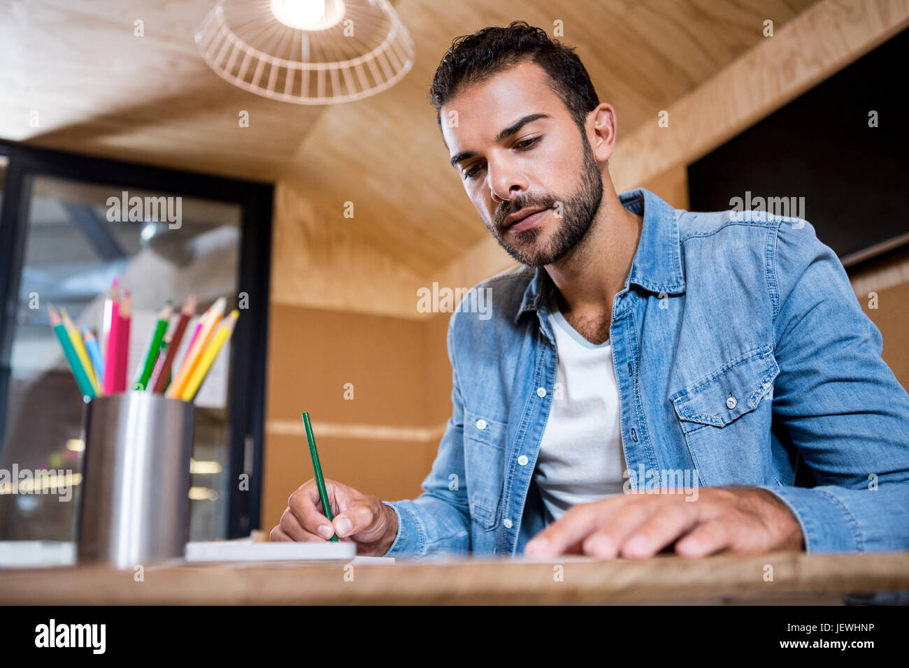 Man in office writing in a notepad Stock Photo - Alamy