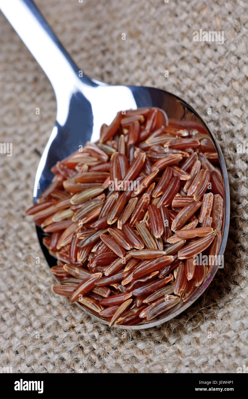 Silver spoon with red rice on table Stock Photo - Alamy