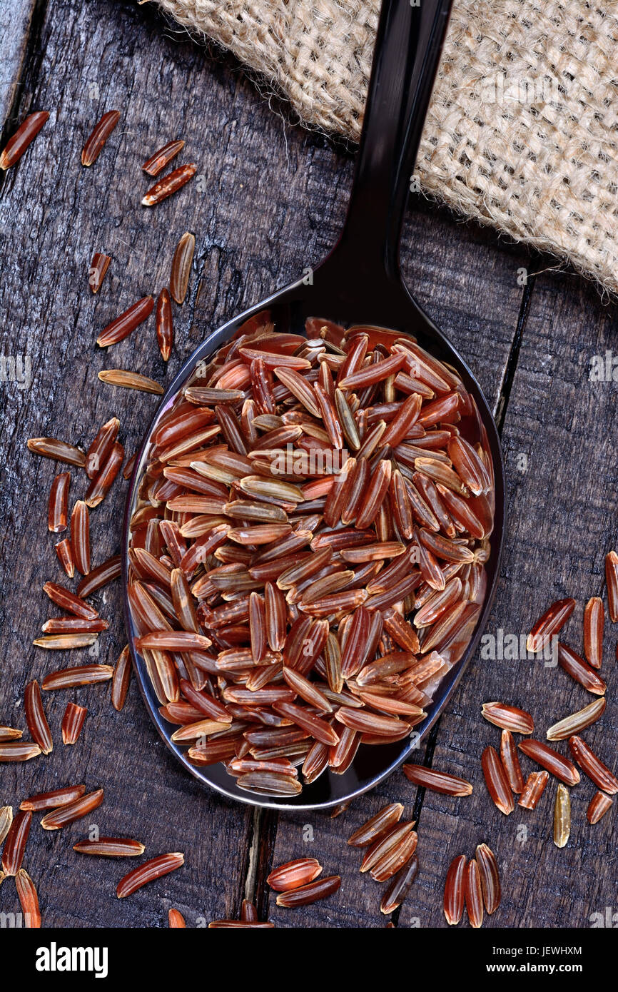 Red rice in a silver spoon on table Stock Photo - Alamy