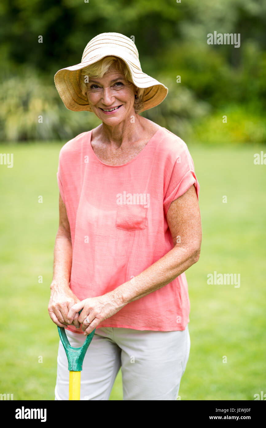 Senior woman with rake standing in yard Stock Photo - Alamy