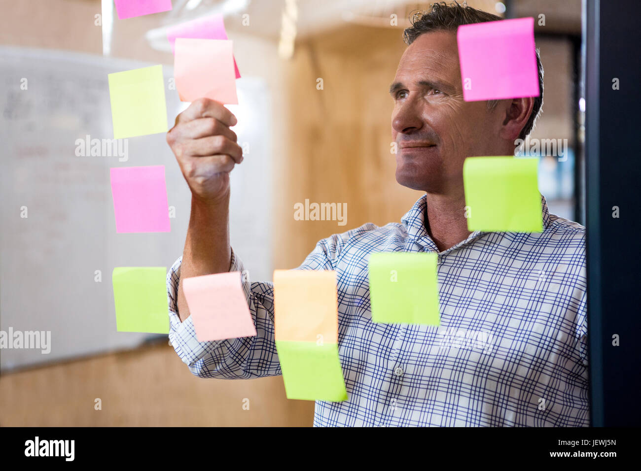 Man looking at sticky notes on window Stock Photo - Alamy