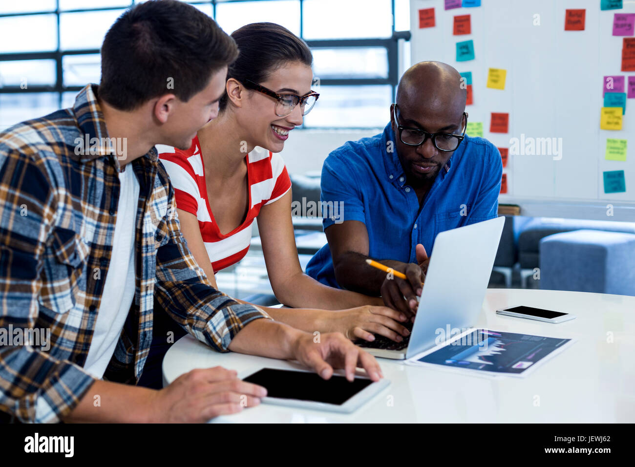 Colleagues interact using laptop at desk Stock Photo - Alamy