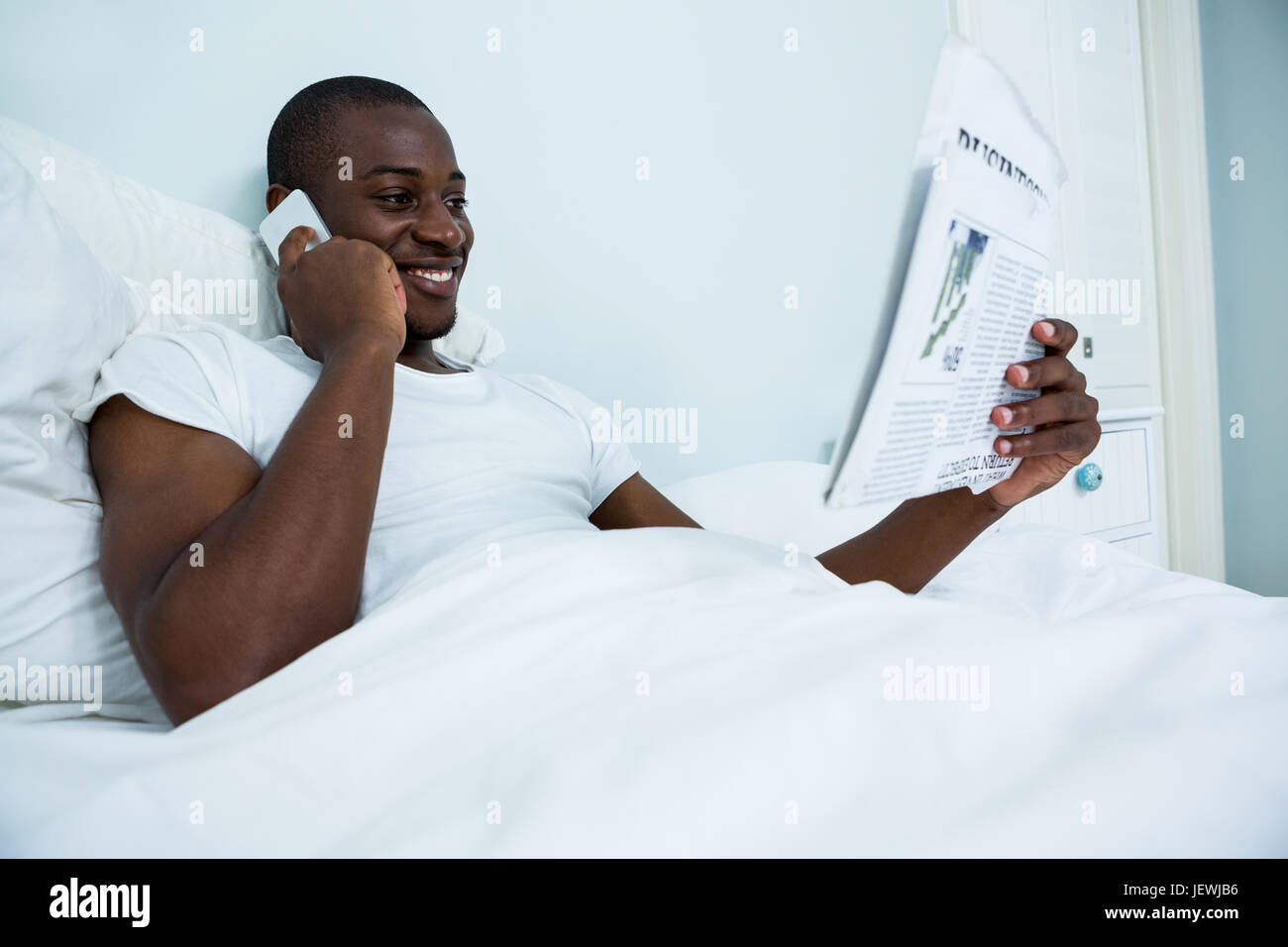 Man reading newspaper while talking on phone Stock Photo - Alamy
