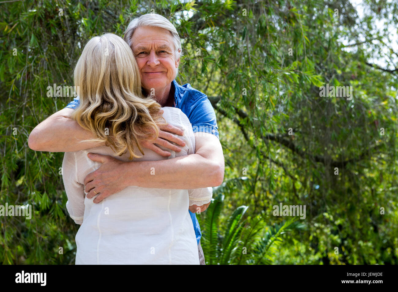 Senior man hugging woman at park Stock Photo - Alamy