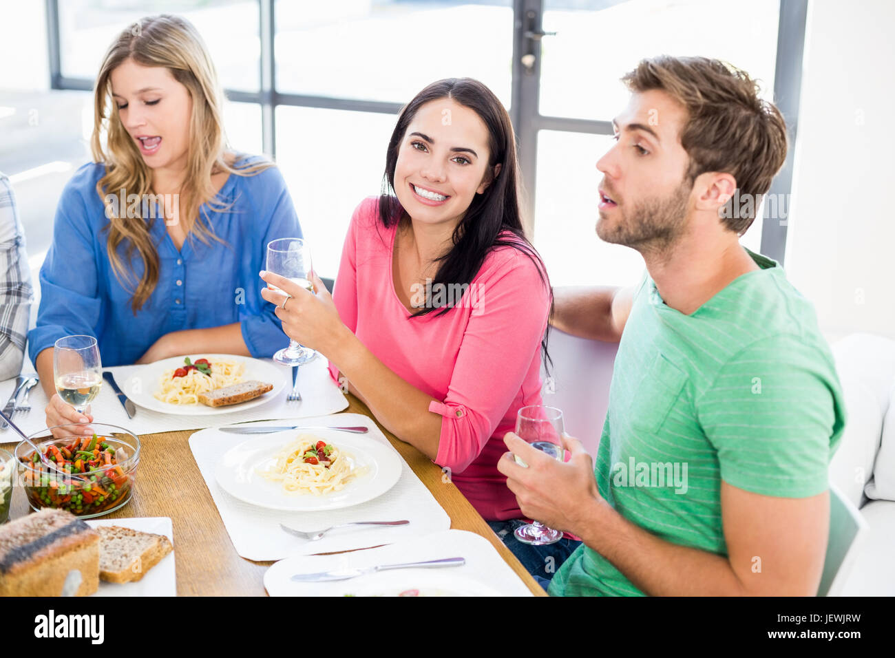 Woman sitting with friends at dinning table Stock Photo - Alamy