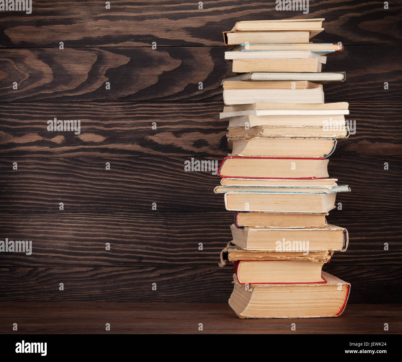 Stack of old books in front of wooden wall. School background ...
