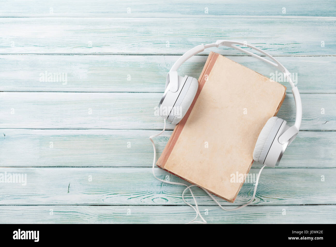 Audio book concept. Headphones and old book over wooden table. Top view ...