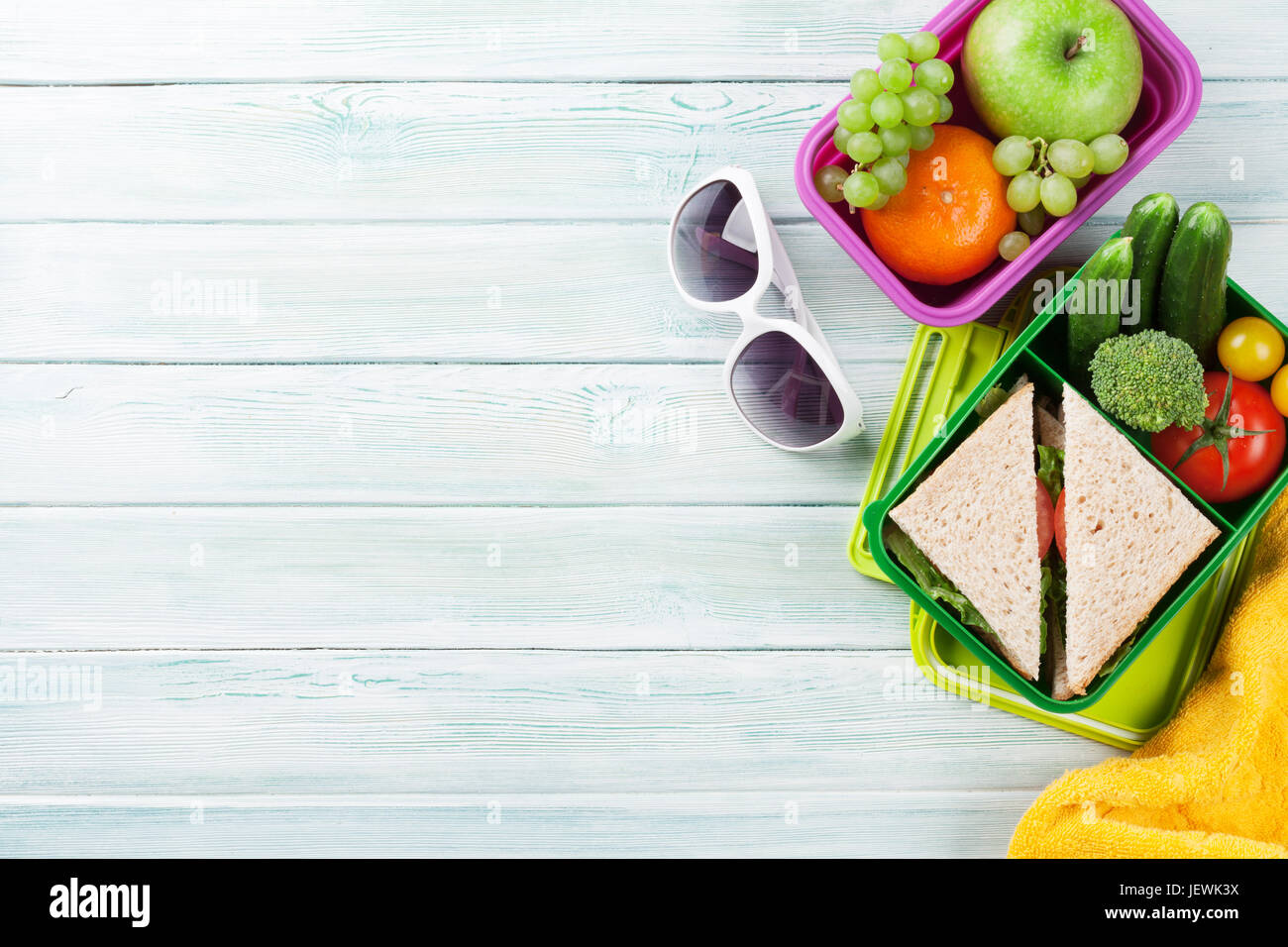 Lunch box with vegetables and sandwich on wooden background. Beach take ...