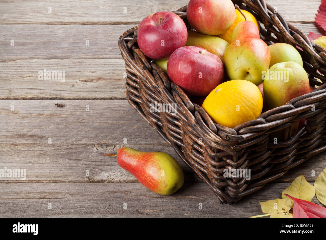 Autumn fruits box and colorful leaves on wooden table. View with copy ...