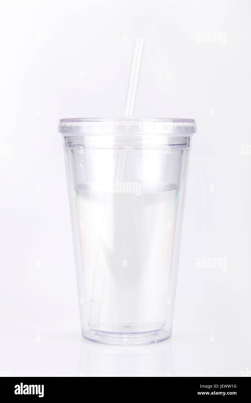 Clear plastic tumbler glass with lid and straw on a white surface ...