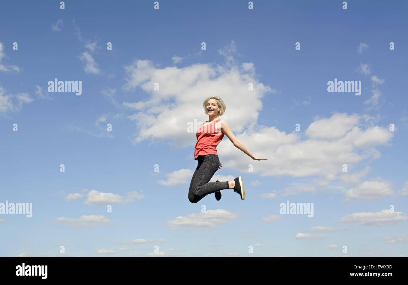 joyful young blond woman leaping Stock Photo - Alamy