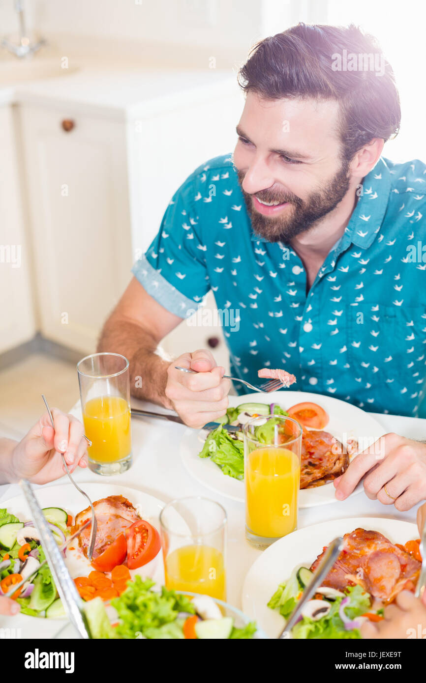 Young man sitting at dining table smiling Stock Photo - Alamy