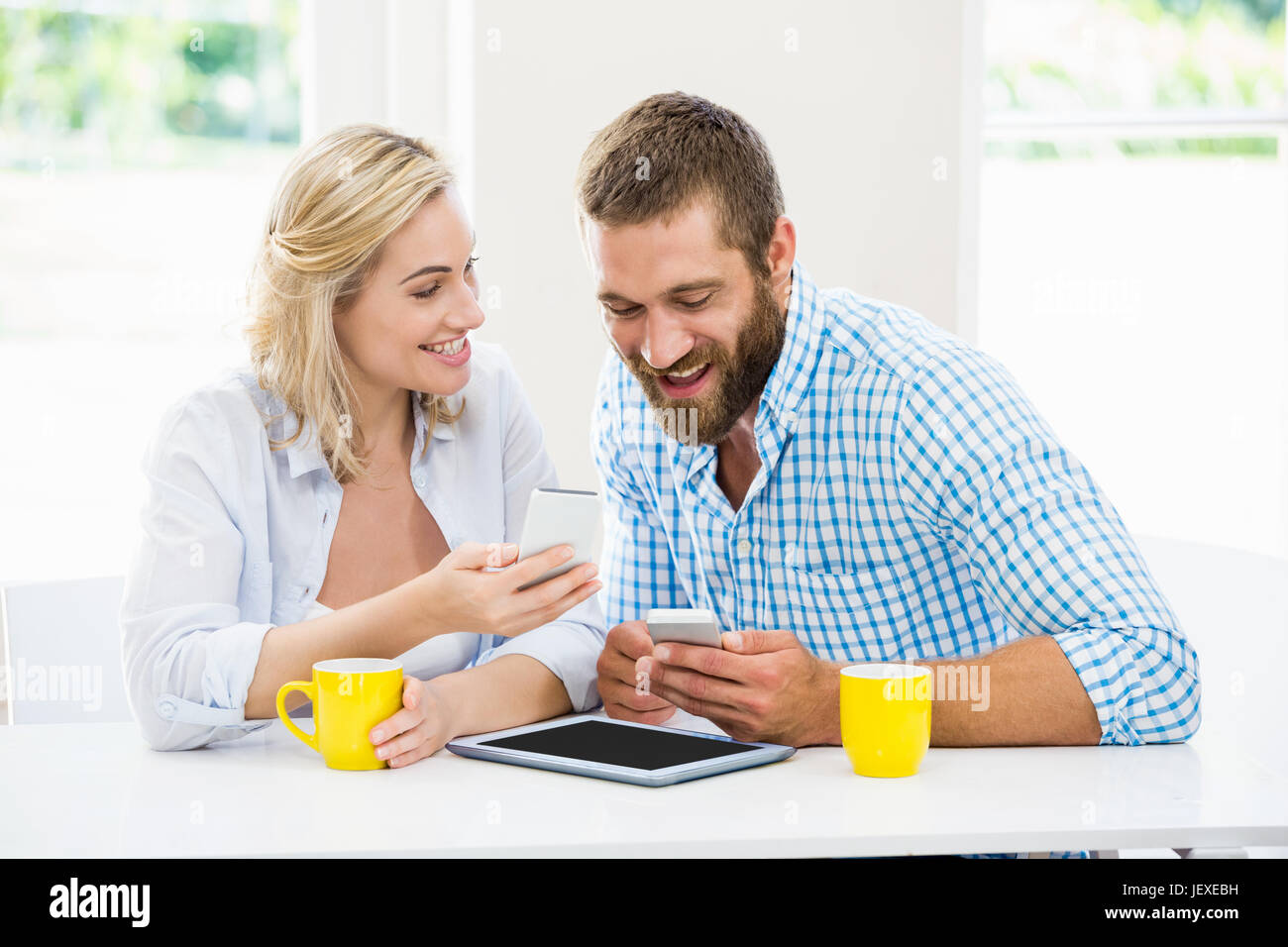 Smiling couple using a mobile phone Stock Photo - Alamy