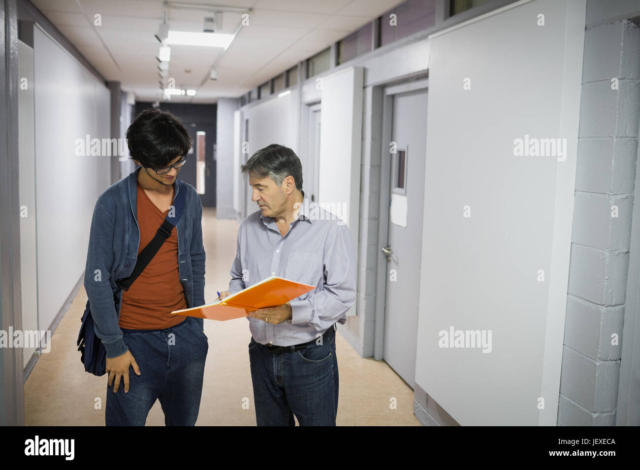 Professor with notebook talking to a student Stock Photo - Alamy