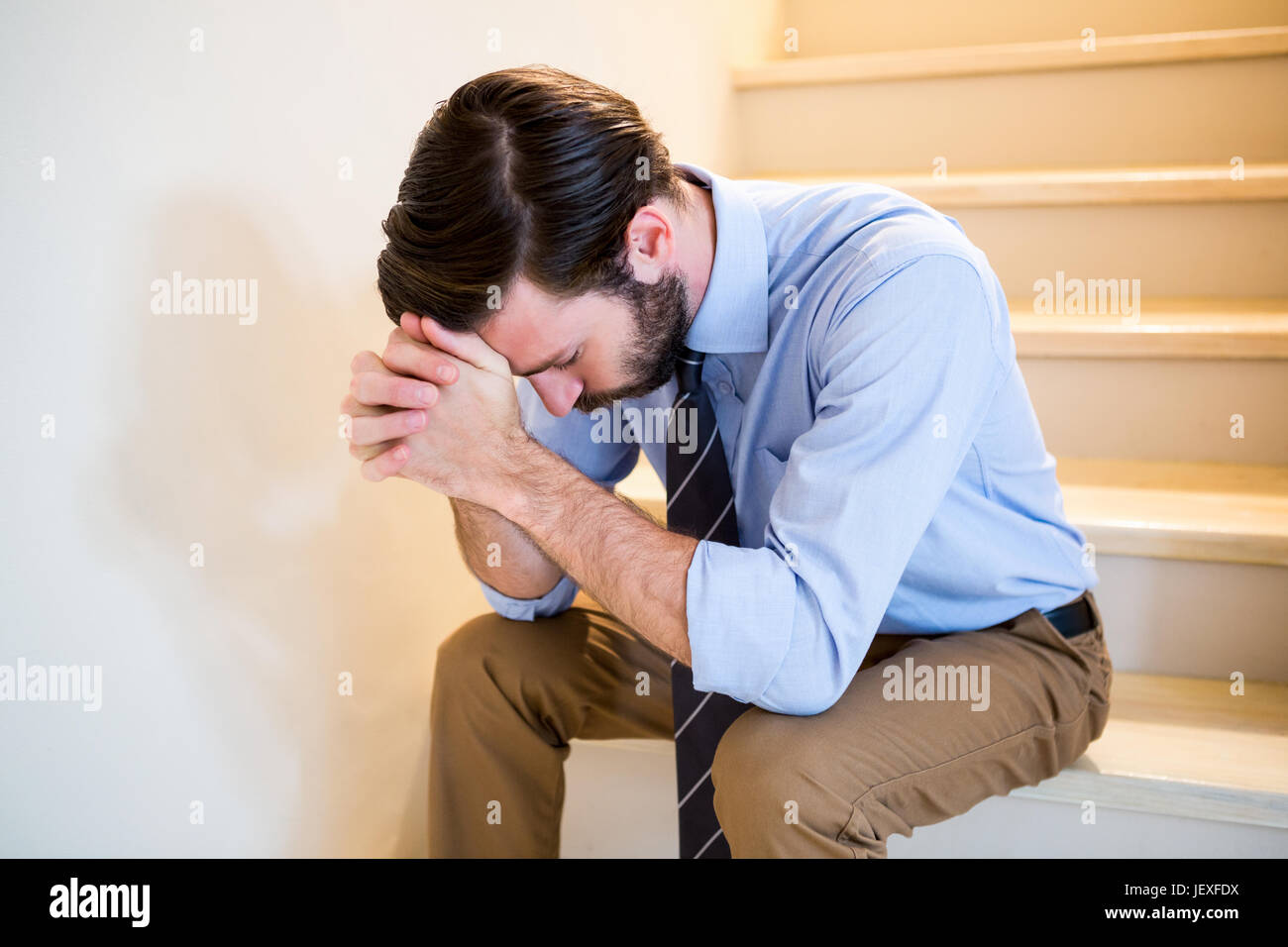 Worried man sitting on stairs Stock Photo - Alamy