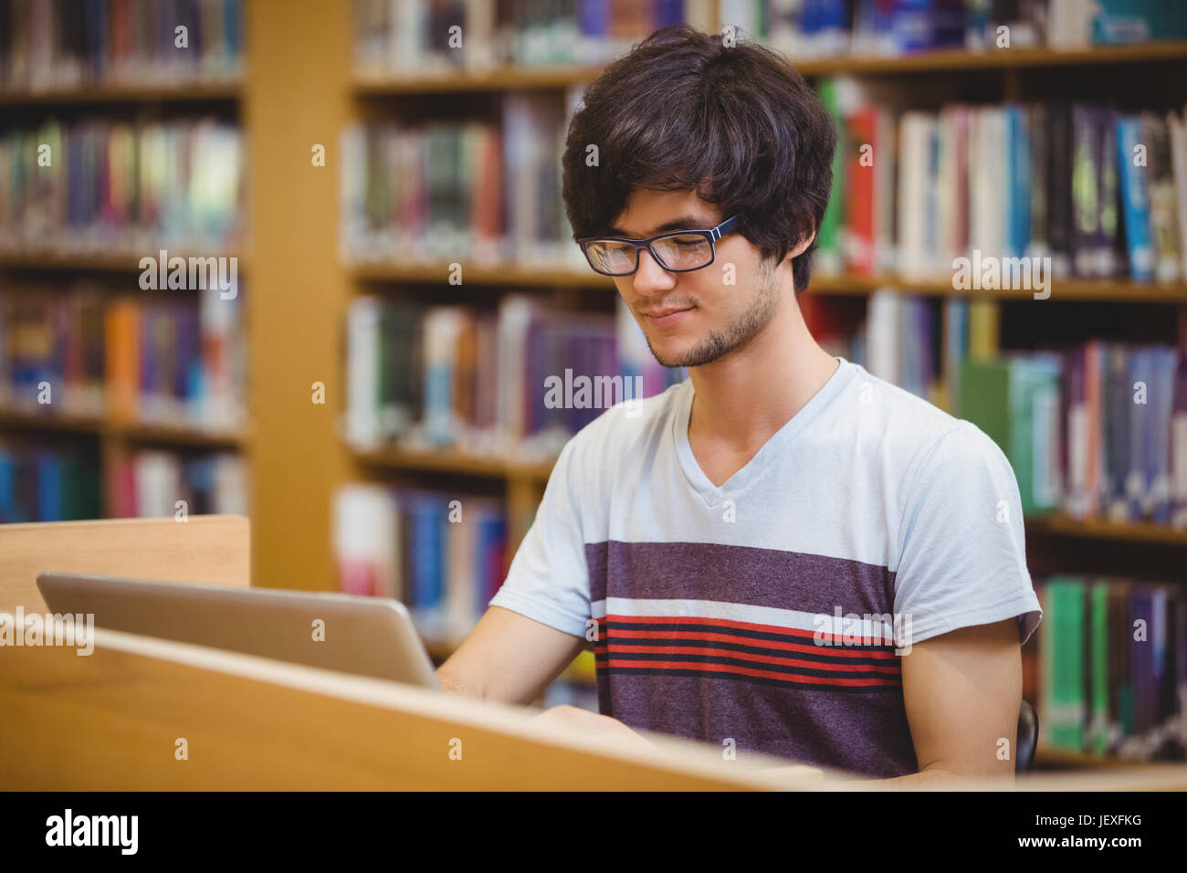 Young student using his laptop in library Stock Photo - Alamy