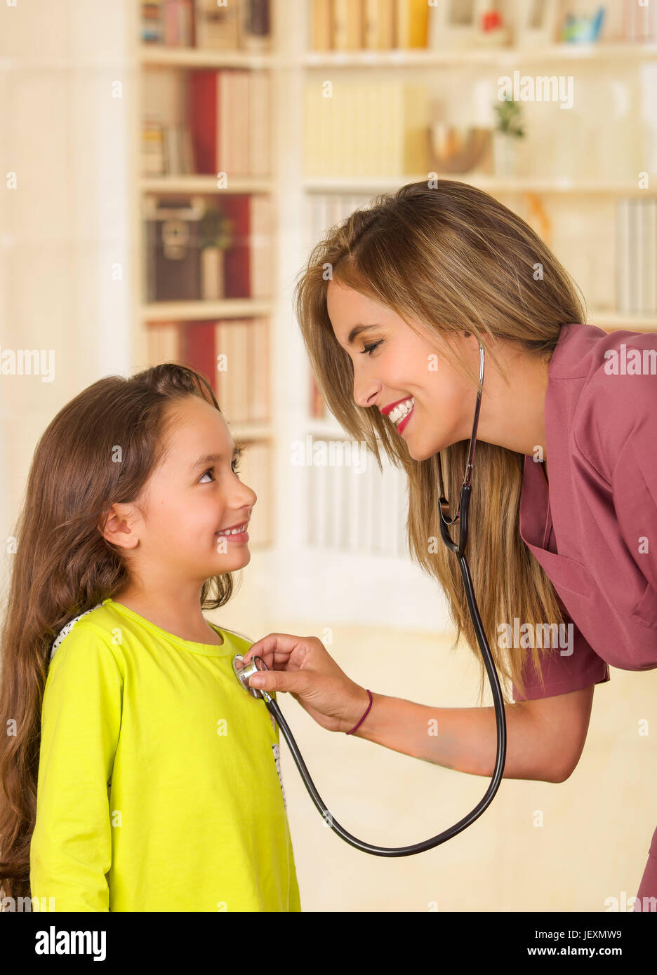 Young pretty girl smiling while a beautiful smiling doctor examining ...