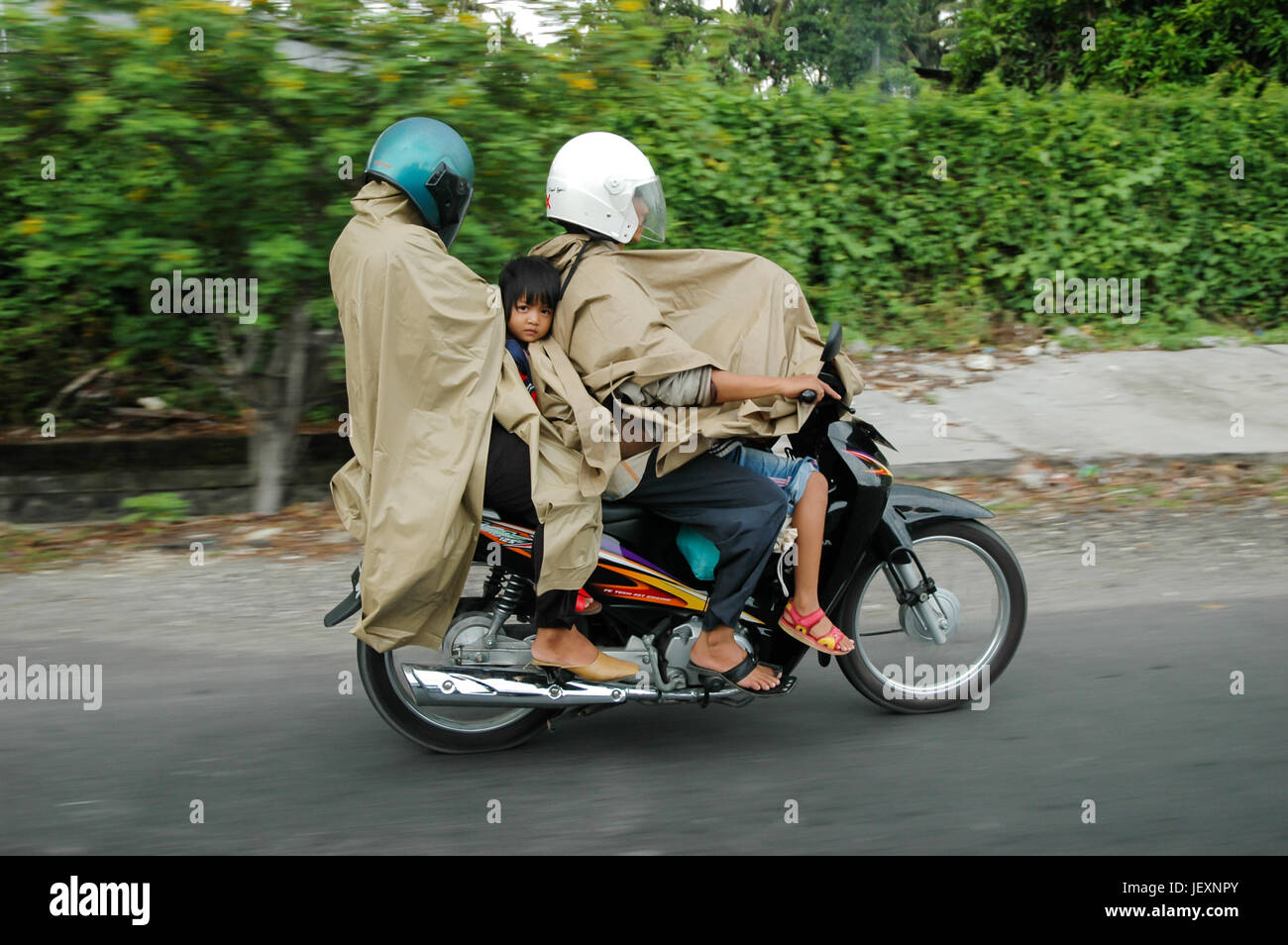 Family commute on small motorcycle with small child without helmet ...