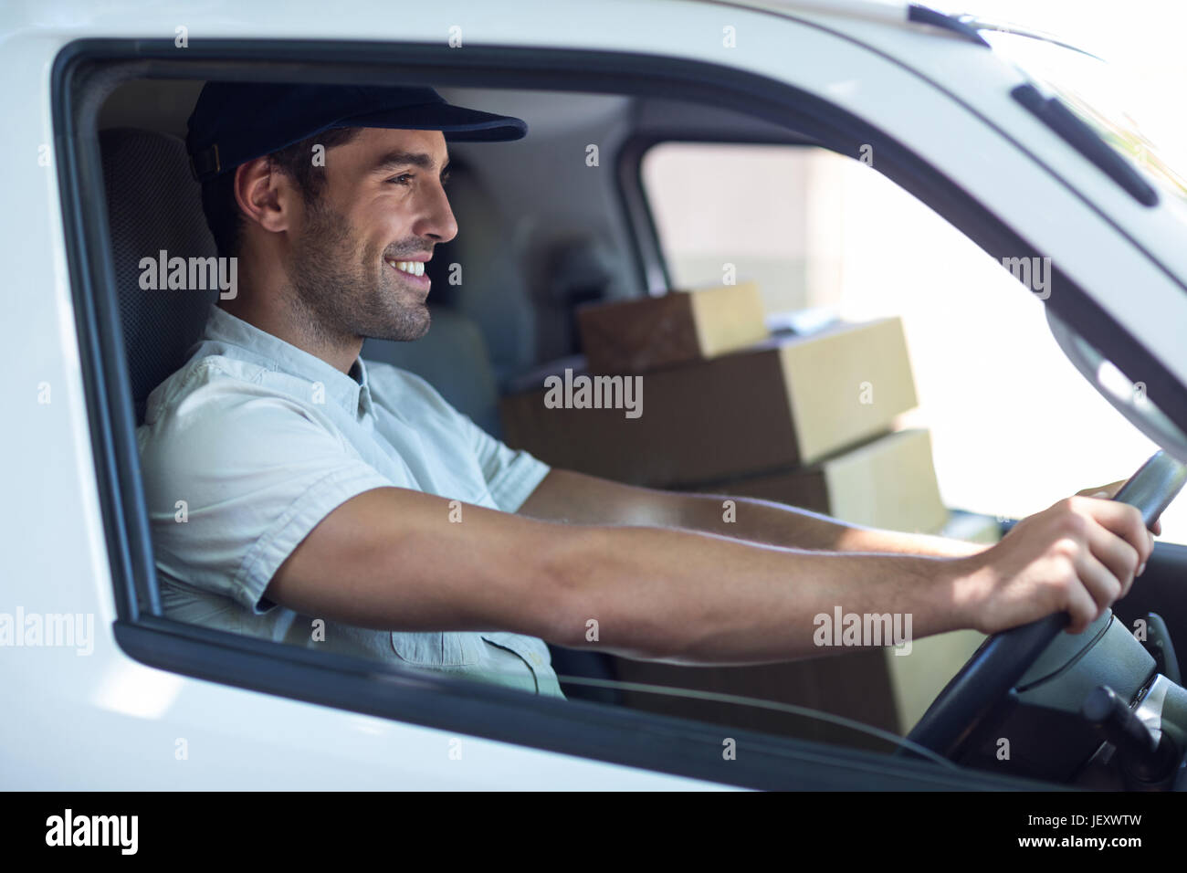 Smiling delivery man driving van Stock Photo - Alamy