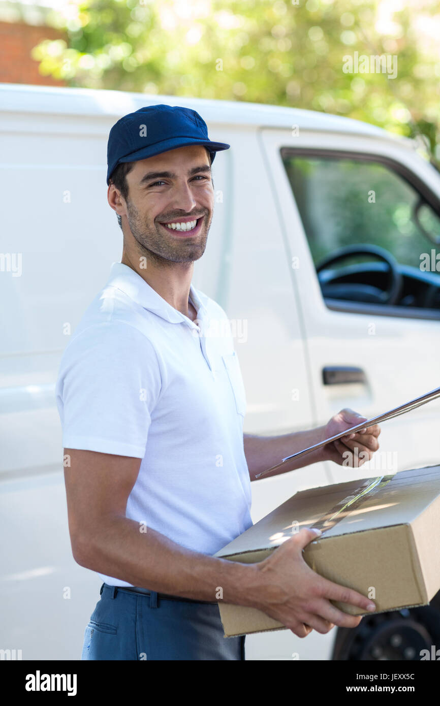 Cheerful delivery man carrying cardboard box Stock Photo - Alamy