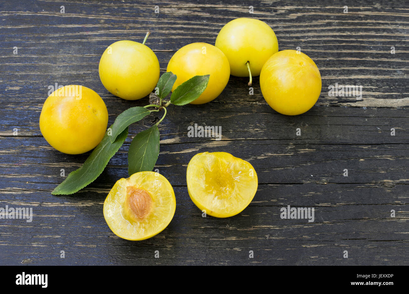 Yellow plum fruits with green leaves on wooden background Stock Photo ...
