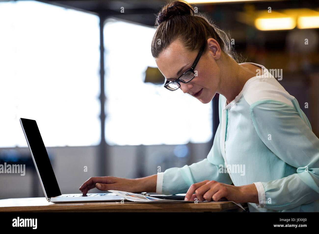 Woman looking a chart and using a laptop Stock Photo - Alamy