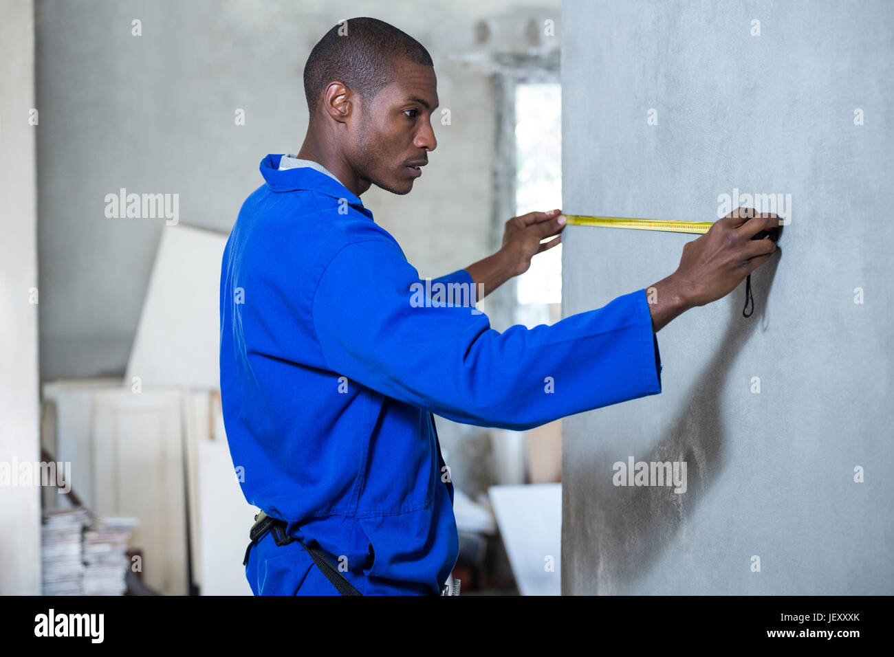 Handyman measuring a wall Stock Photo - Alamy