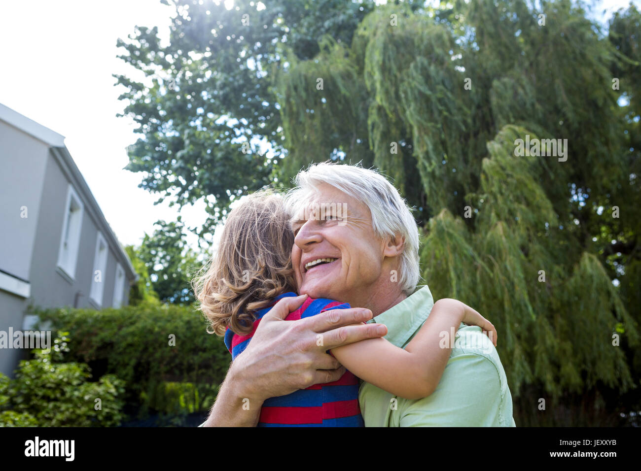 Grandfather hugging grandson at yard Stock Photo - Alamy