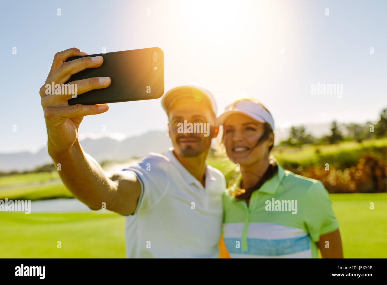 Young couple taking self portrait at golf course. Male and female ...