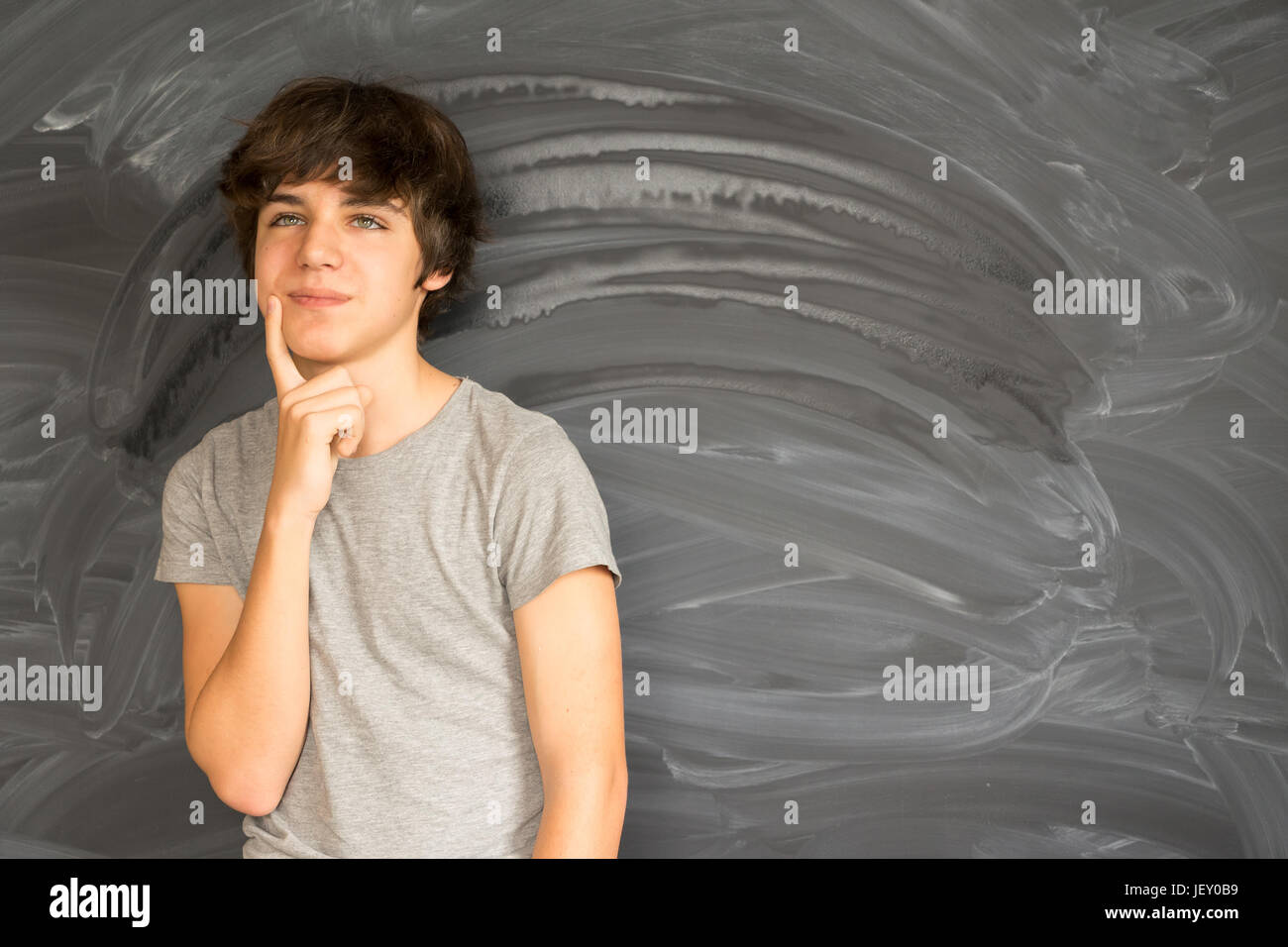 Tennager Boy thinking and getting an idea with empty black board in ...