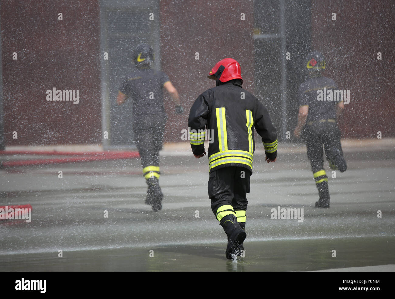 Firefighters run under the splashes of water during fire extinguishing ...