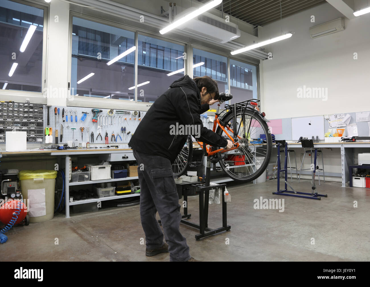 Young mechanic repairing the wheel of the bicycle inside the mechanic ...