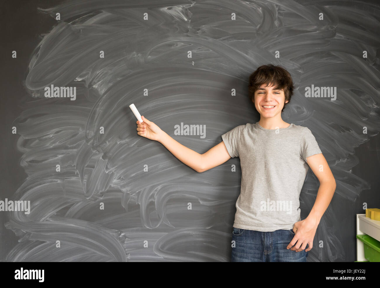 Boy pointing with chalk on empty black board in background Stock Photo ...