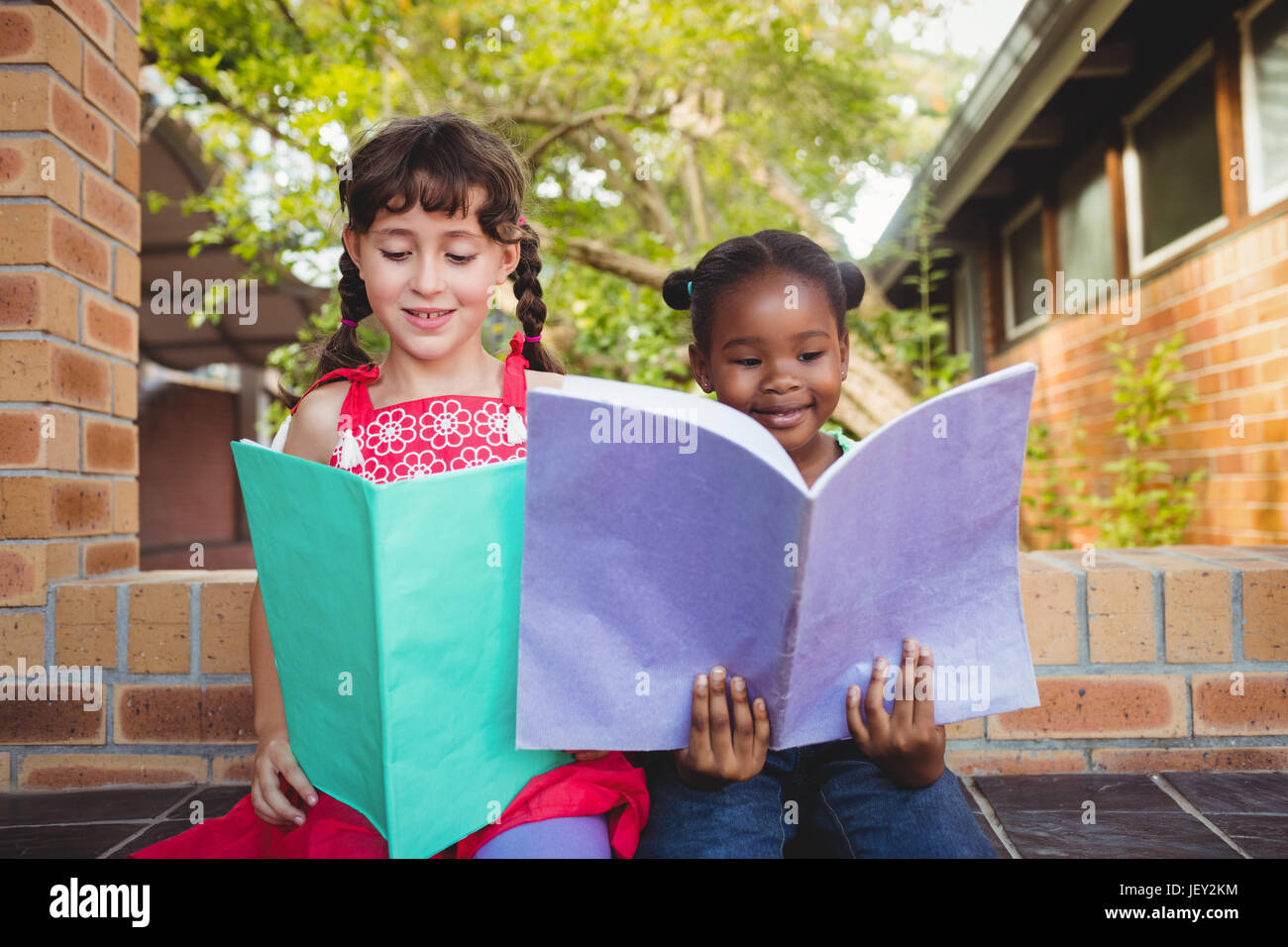 Two children holding a book Stock Photo - Alamy