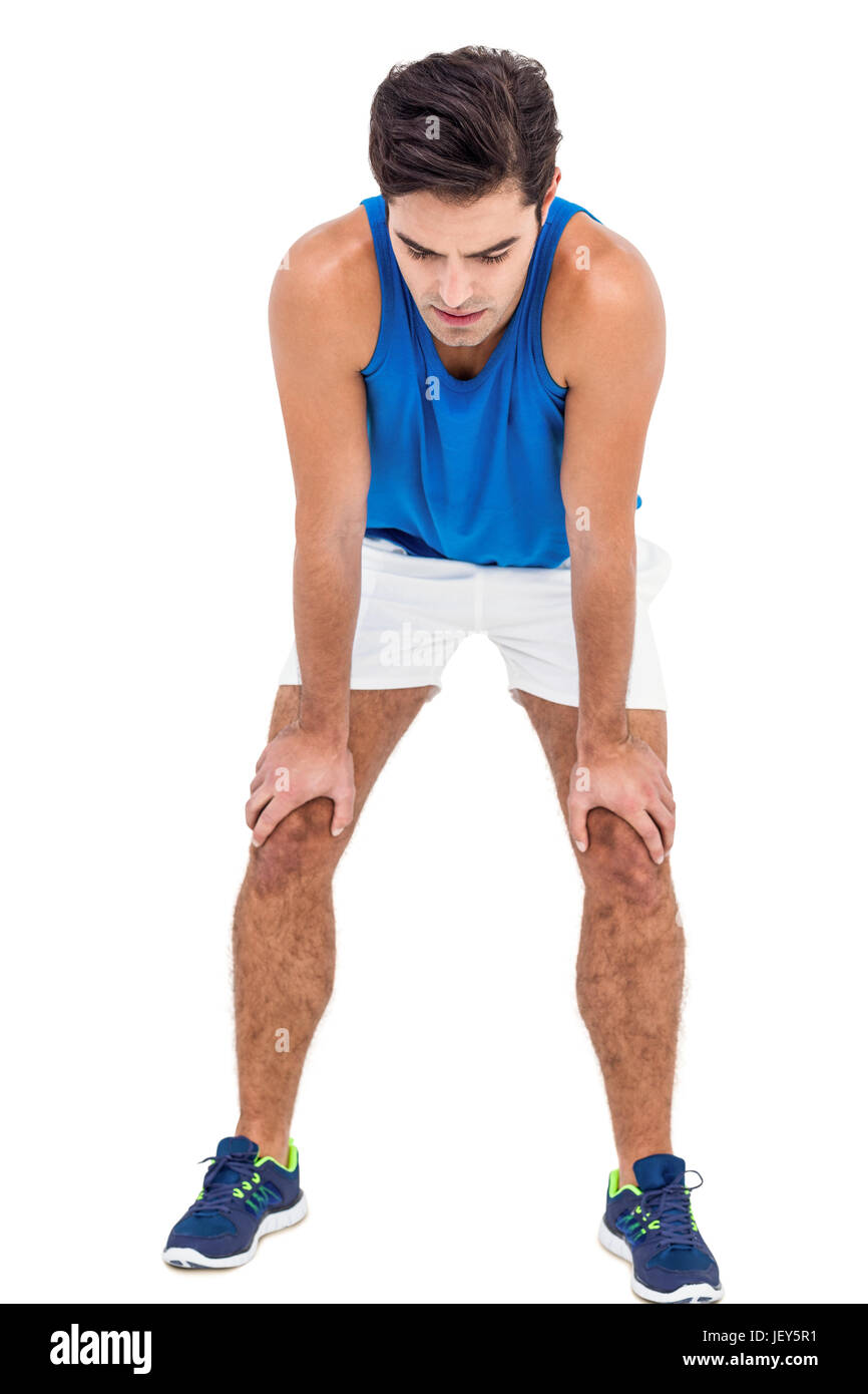 Tired athlete standing with hand on knee Stock Photo - Alamy